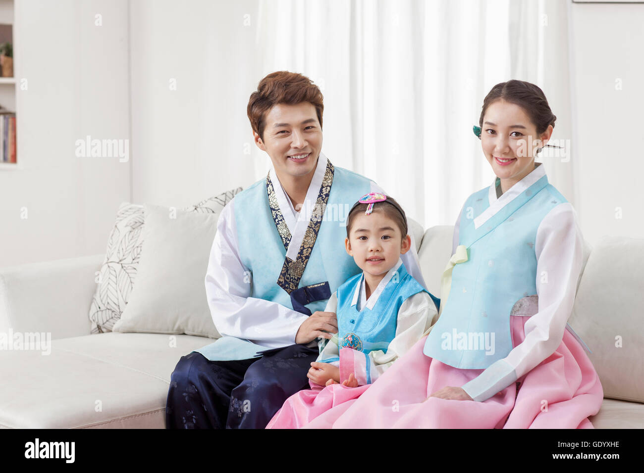Smiling girl with her parents in traditional Korean clothes sitting on ...