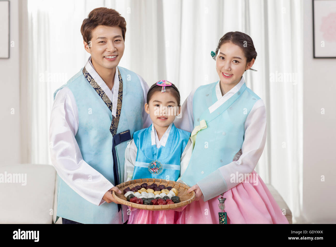 Smiling daughter and her parents in traditional Korean clothes posing ...