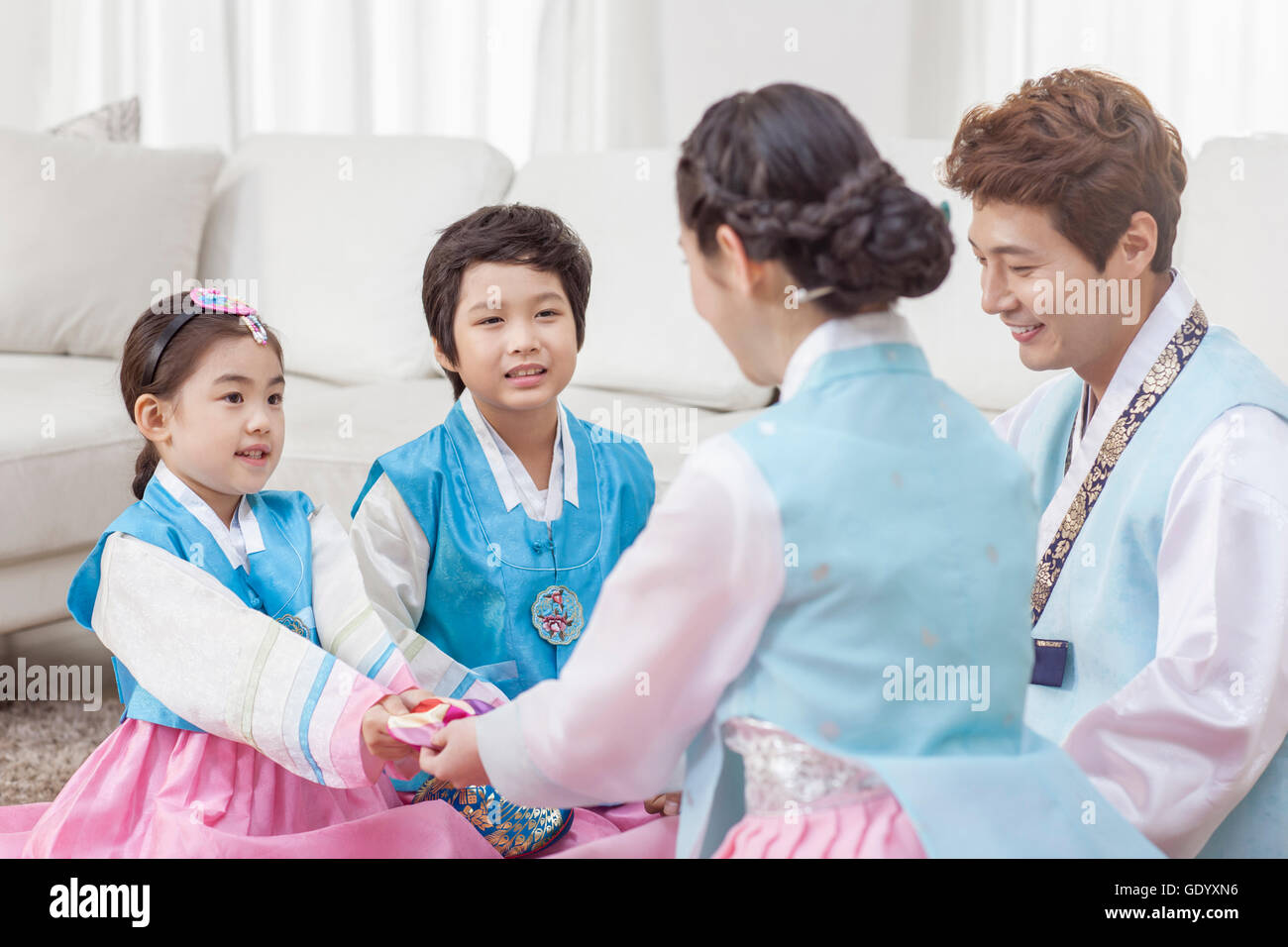 Harmonious family in traditional Korean clothes sitting face to face in ...