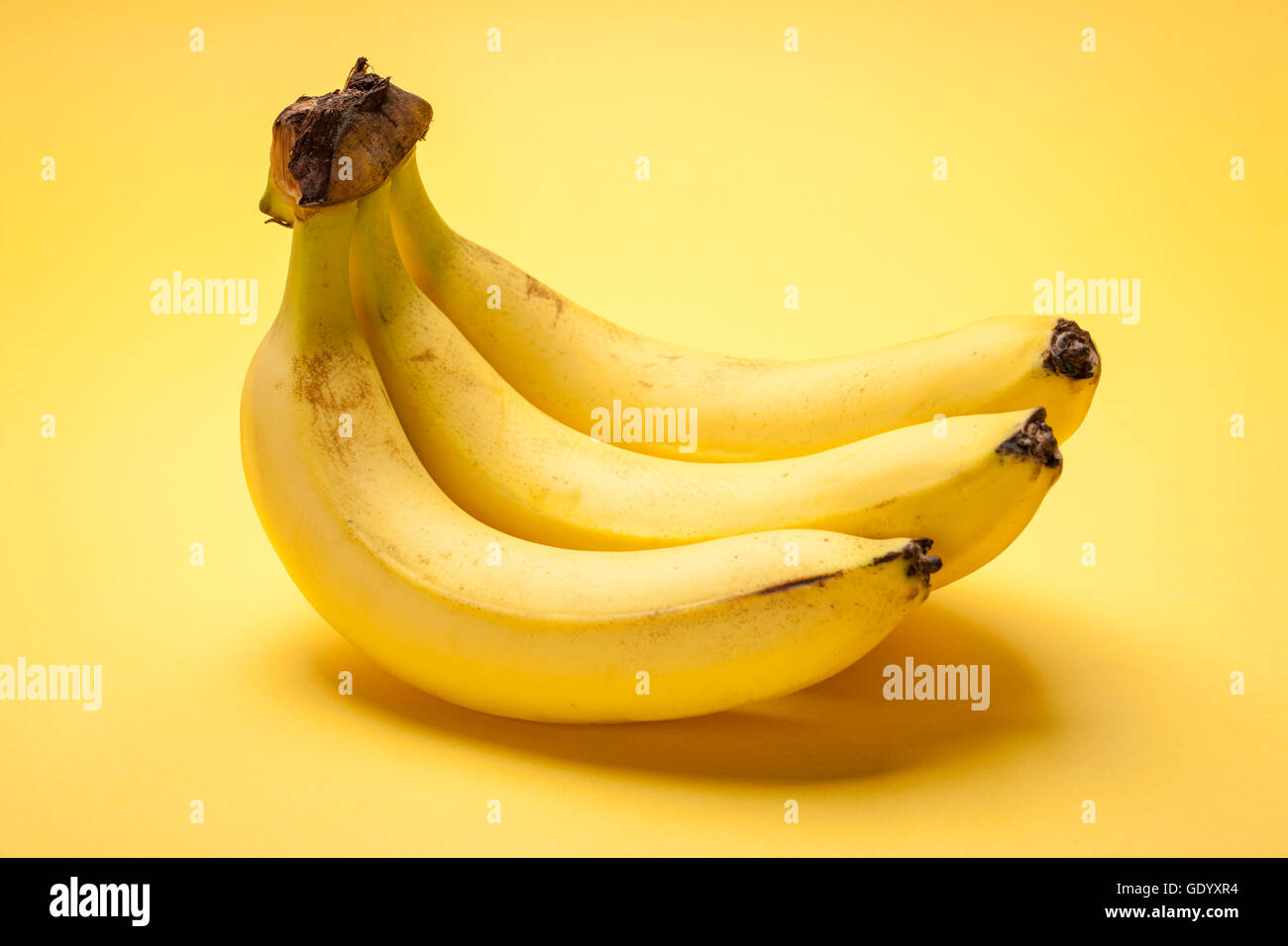 Three yellow bananas against yellow Stock Photo - Alamy