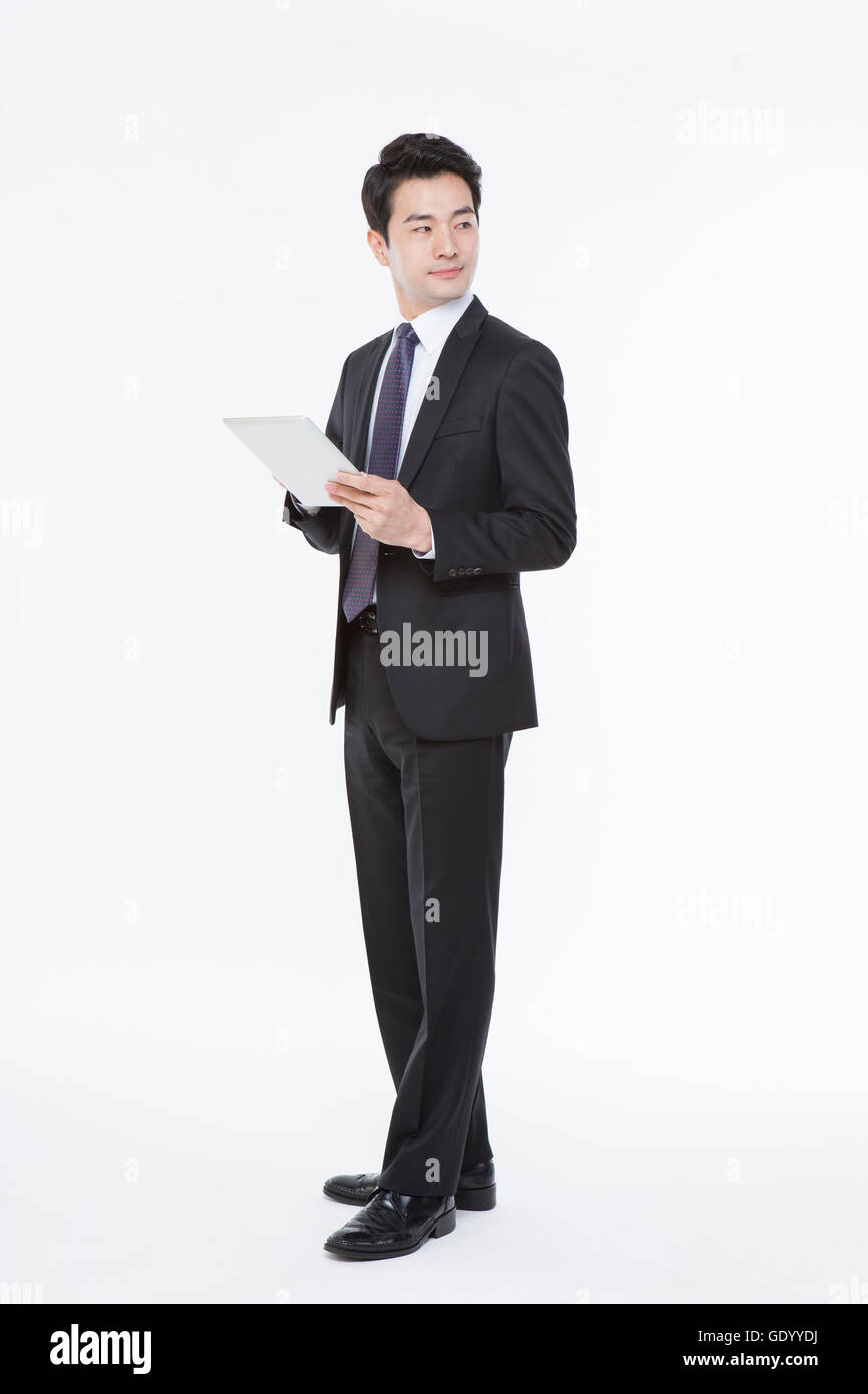 Business man with a tablet standing looking back Stock Photo - Alamy