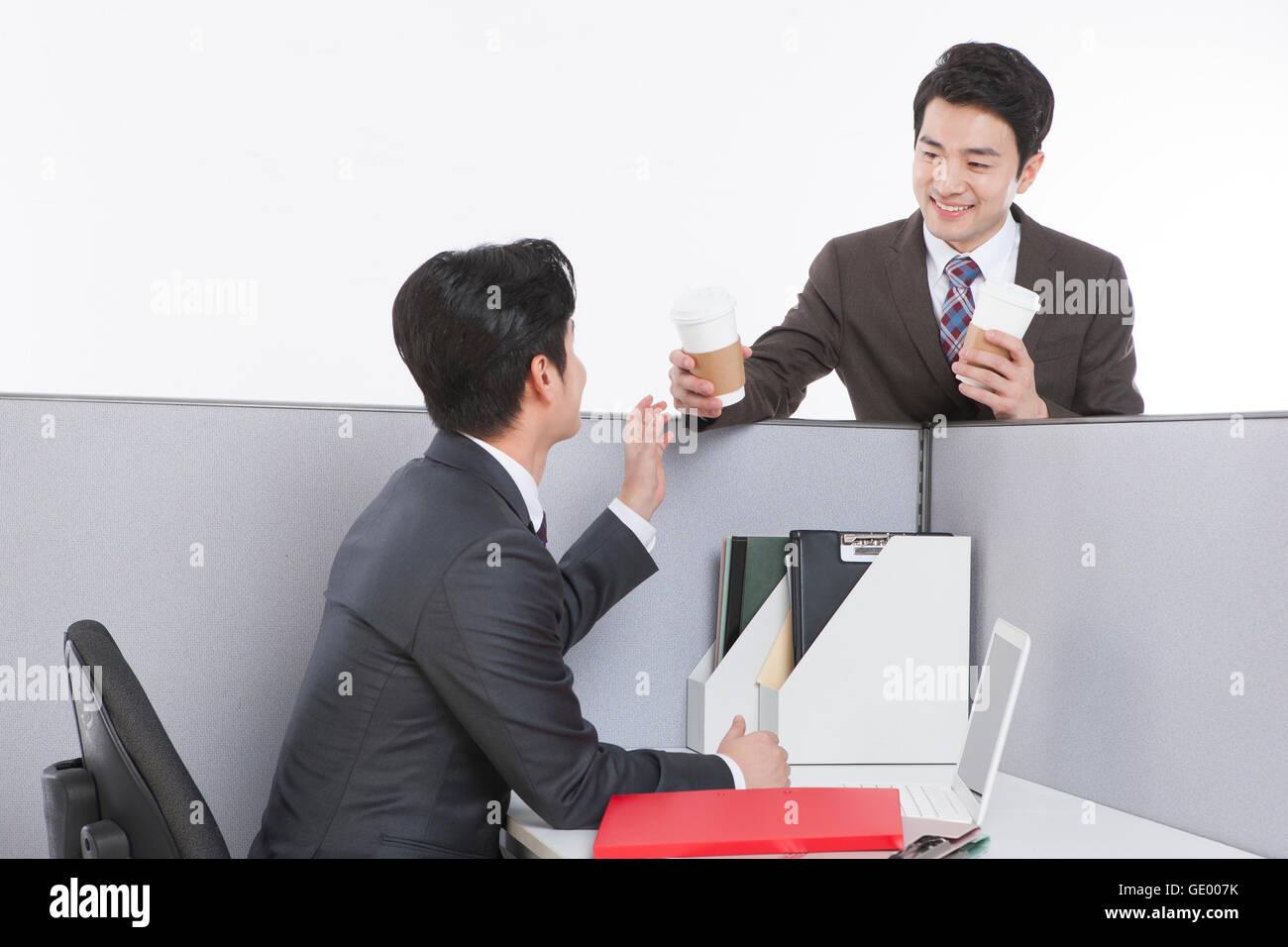 Two smiling business men giving and taking takeout coffee at work Stock ...
