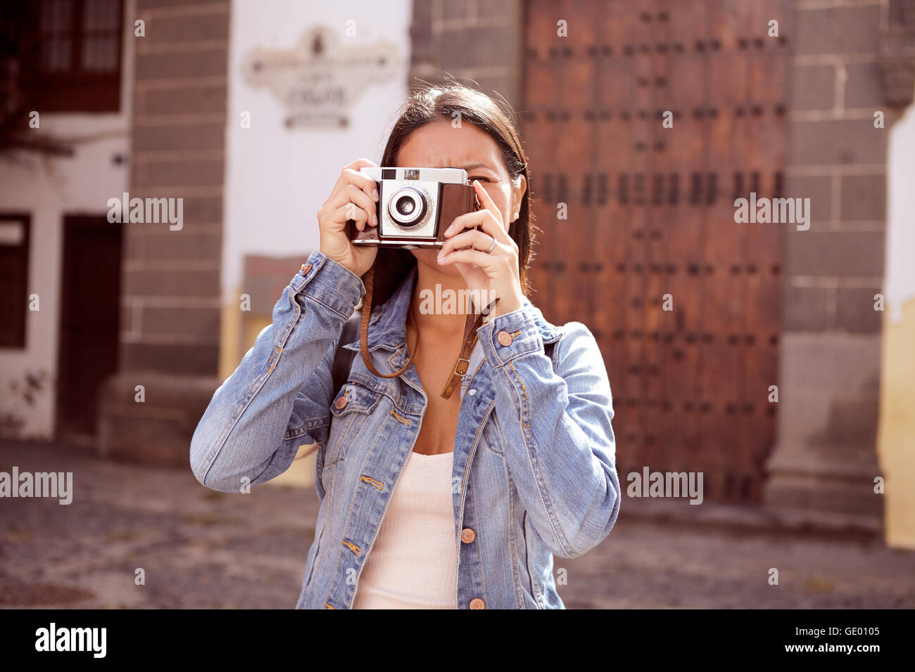 Pretty young girl focusing on taking a picture with her camera, her ...
