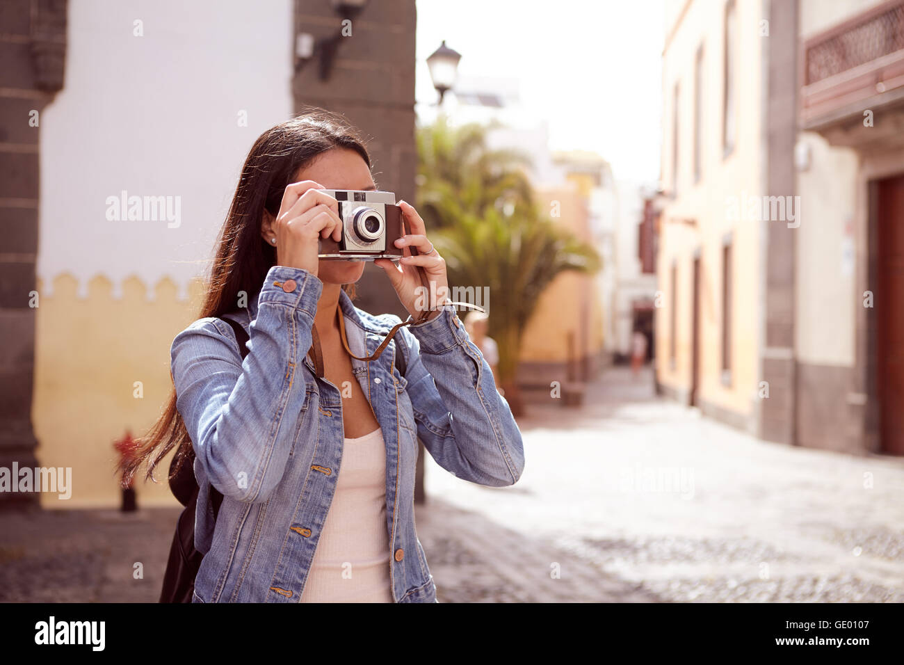 Pretty young girl focusing her camera to take a picture wearing her ...