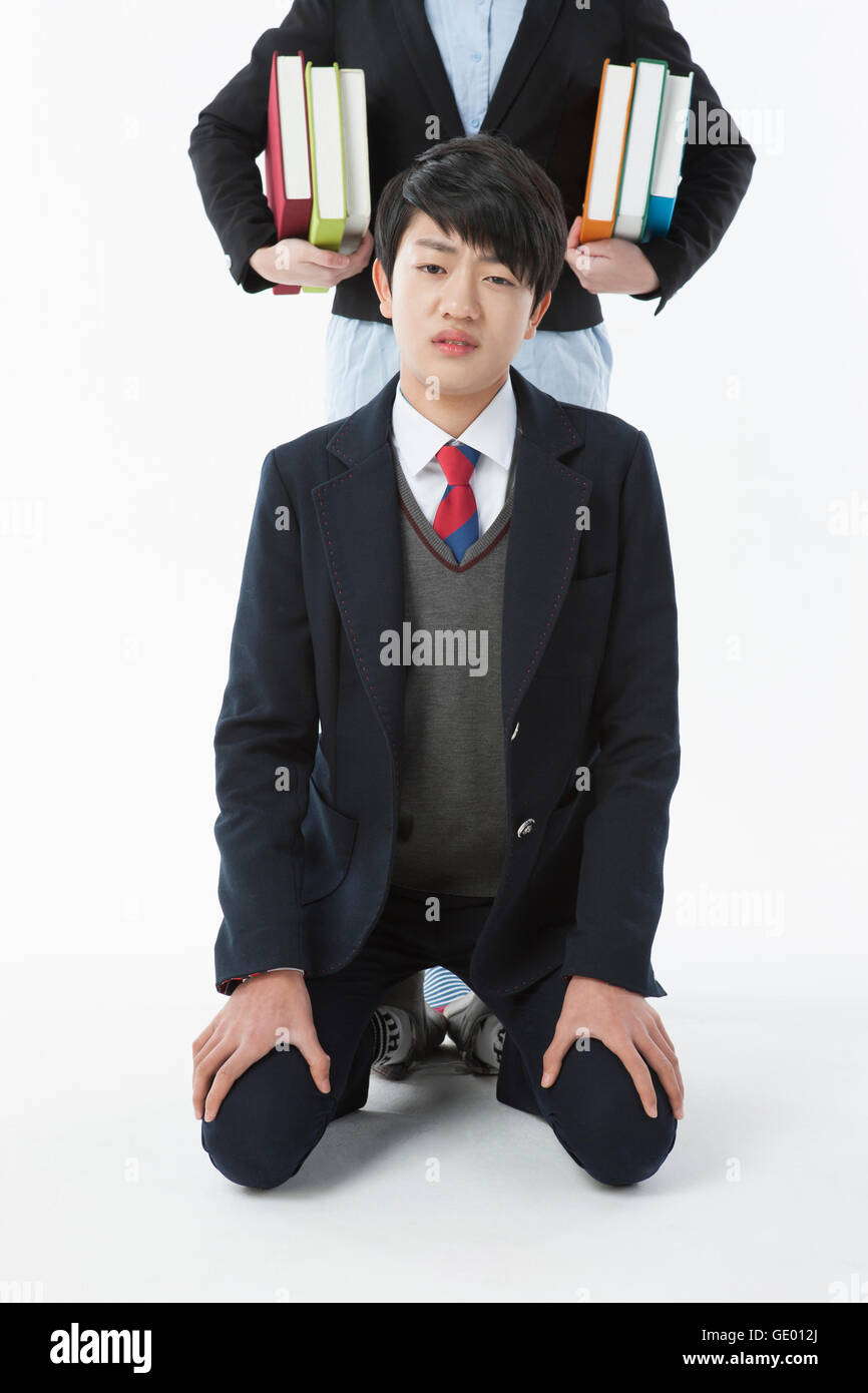 Stressful school boy sitting with a teacher holding books behind him ...