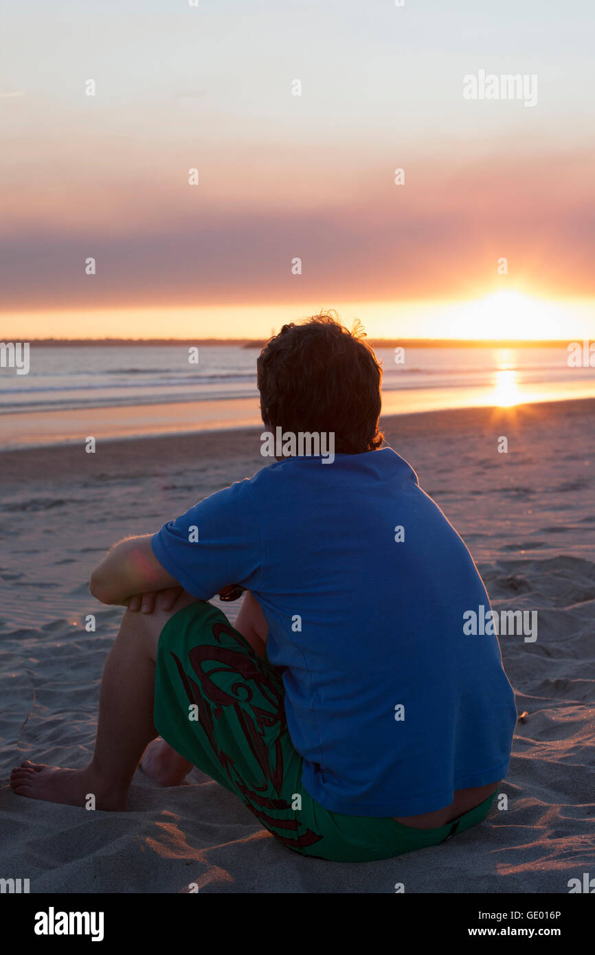 Rear view of a mature man looking at view and sitting on beach, Viana ...