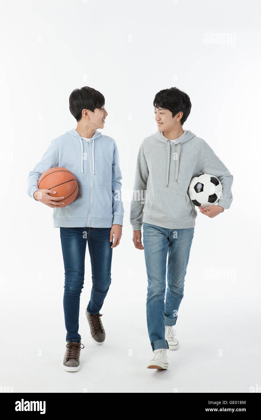 Two smiling school boys with basketball and soccer ball walking face to ...