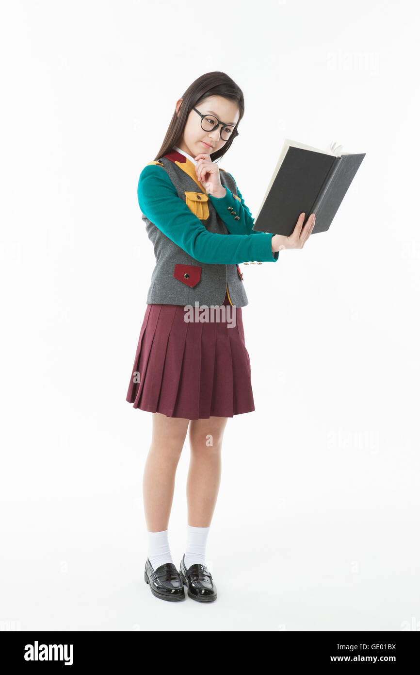 Side view of serious middle school girl standing holding an open book ...