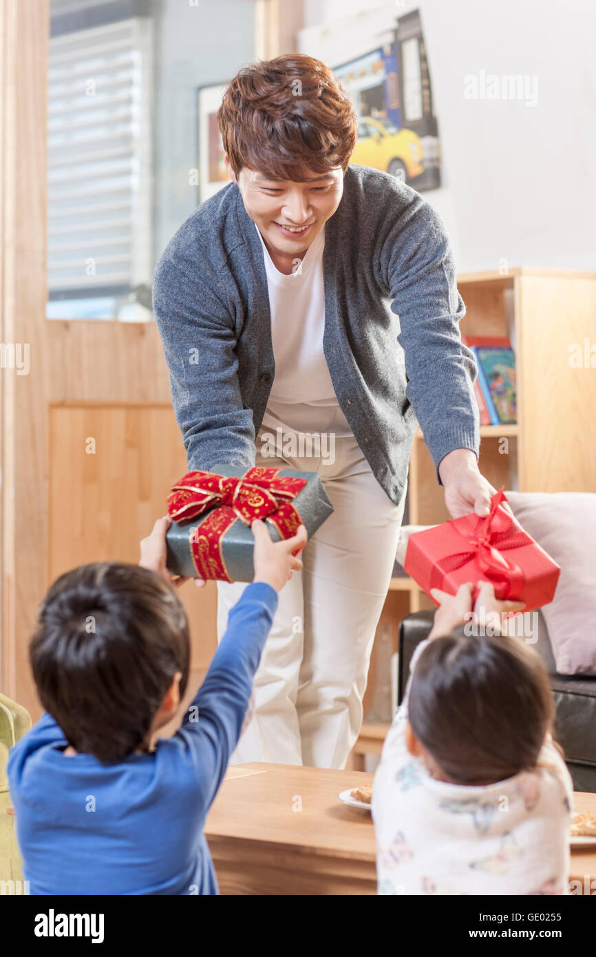 Smiling father giving present boxes to his son and daughter Stock Photo ...