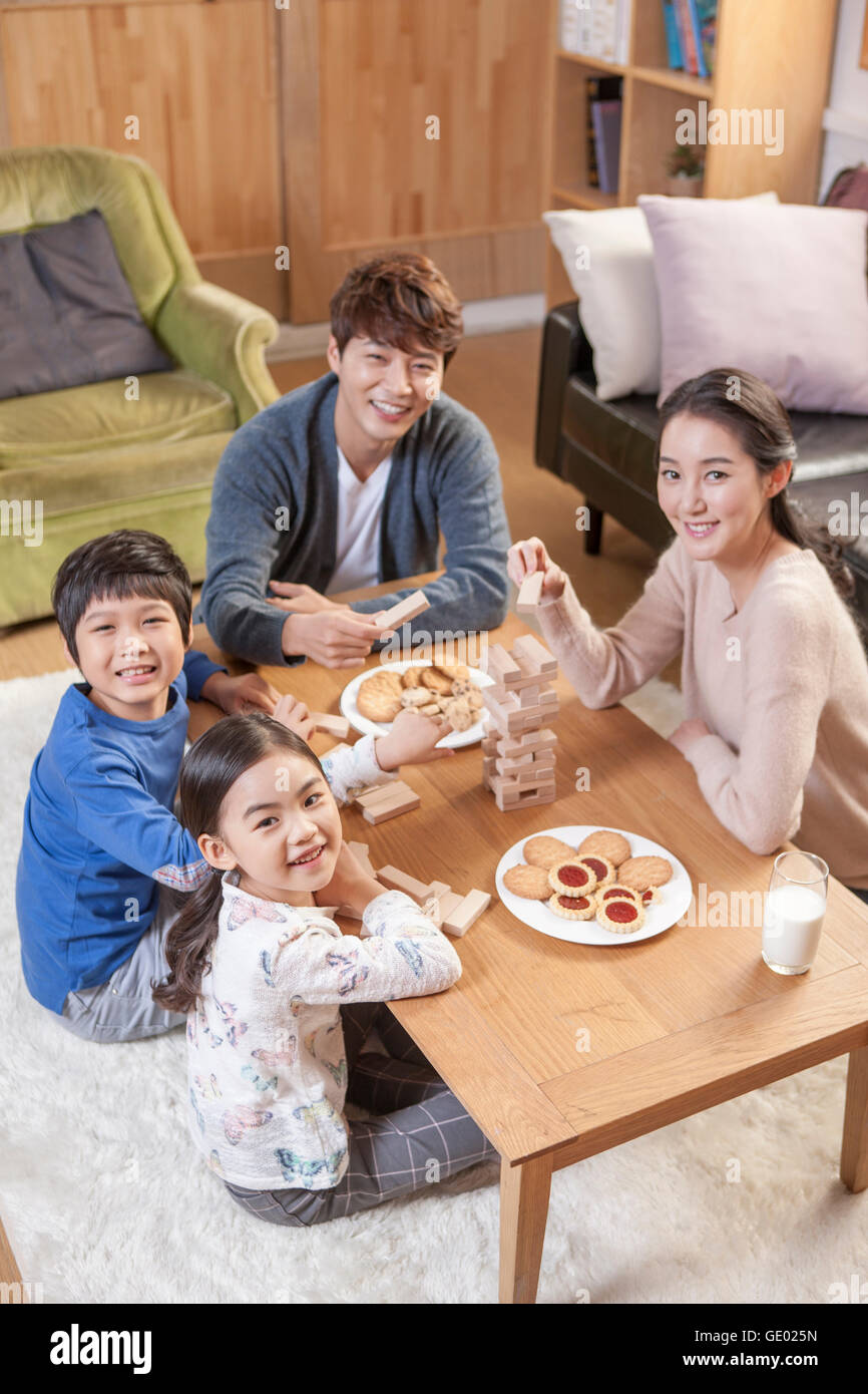 Smiling family eating cookies and playing a game together Stock Photo ...