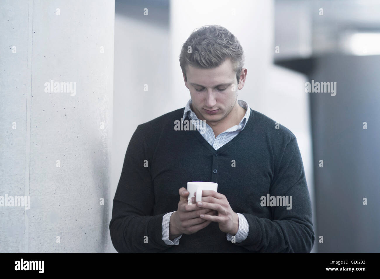 Young businessman drinking coffee and working till late night in office ...