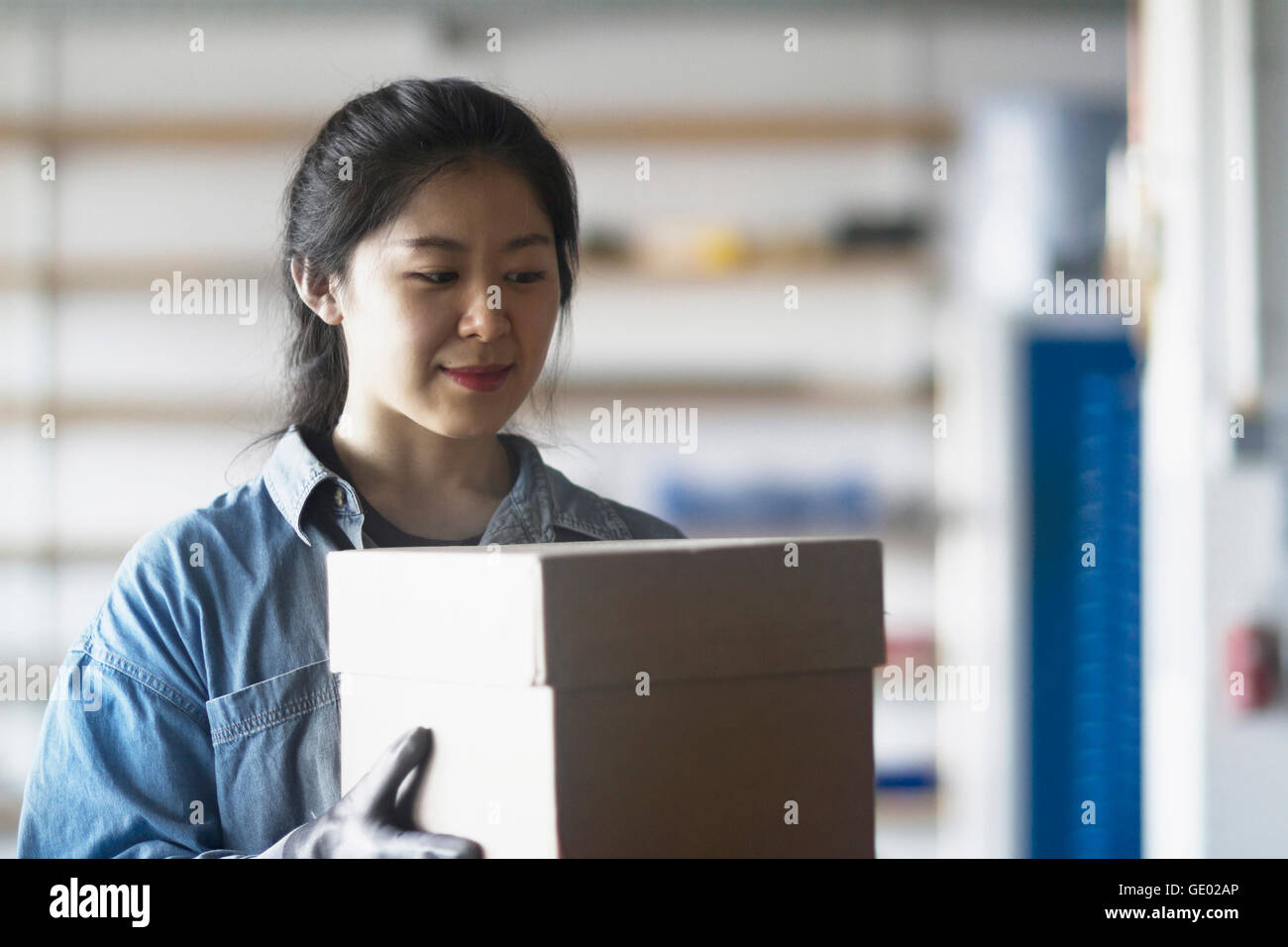 Young female engineer holding cardboard box in an industrial plant ...