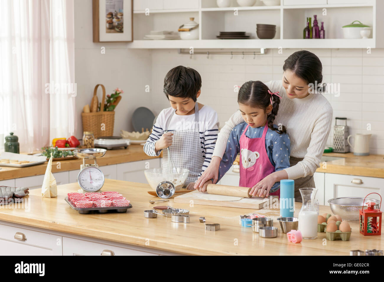 Loving mother helping her daughter and son cooking in kitchen Stock ...