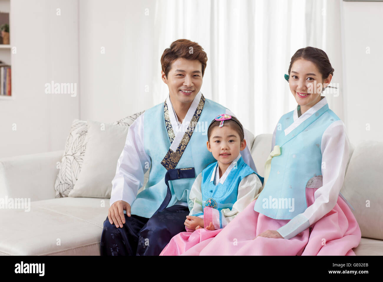 Smiling family in traditional Korean clothes sitting on sofa Stock ...