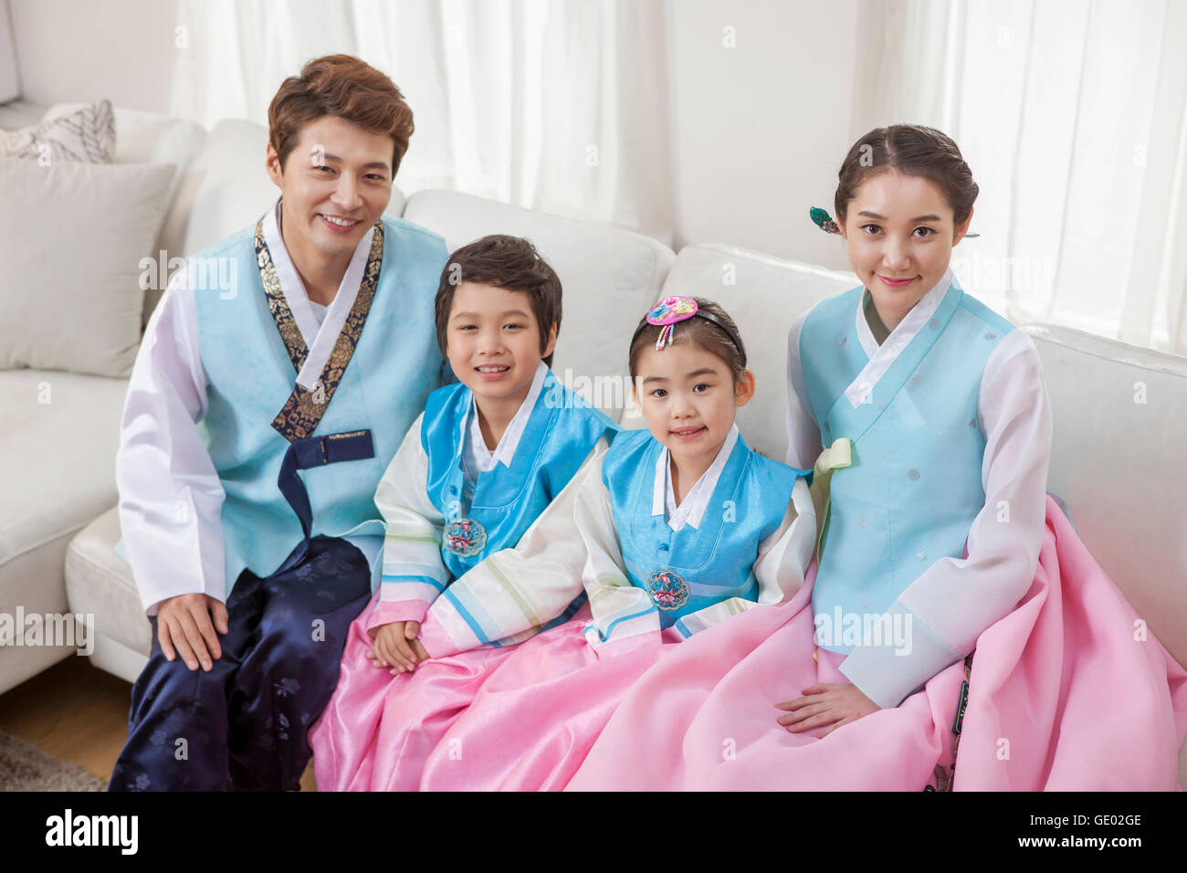 Harmonious Korean family in traditional Korean clothes sitting on sofa ...