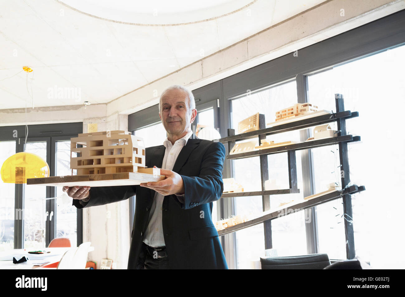 Portrait of a senior architect showing architectural model in the ...