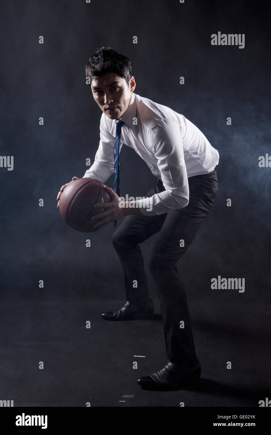 Business man posing with a basketball staring at front Stock Photo - Alamy