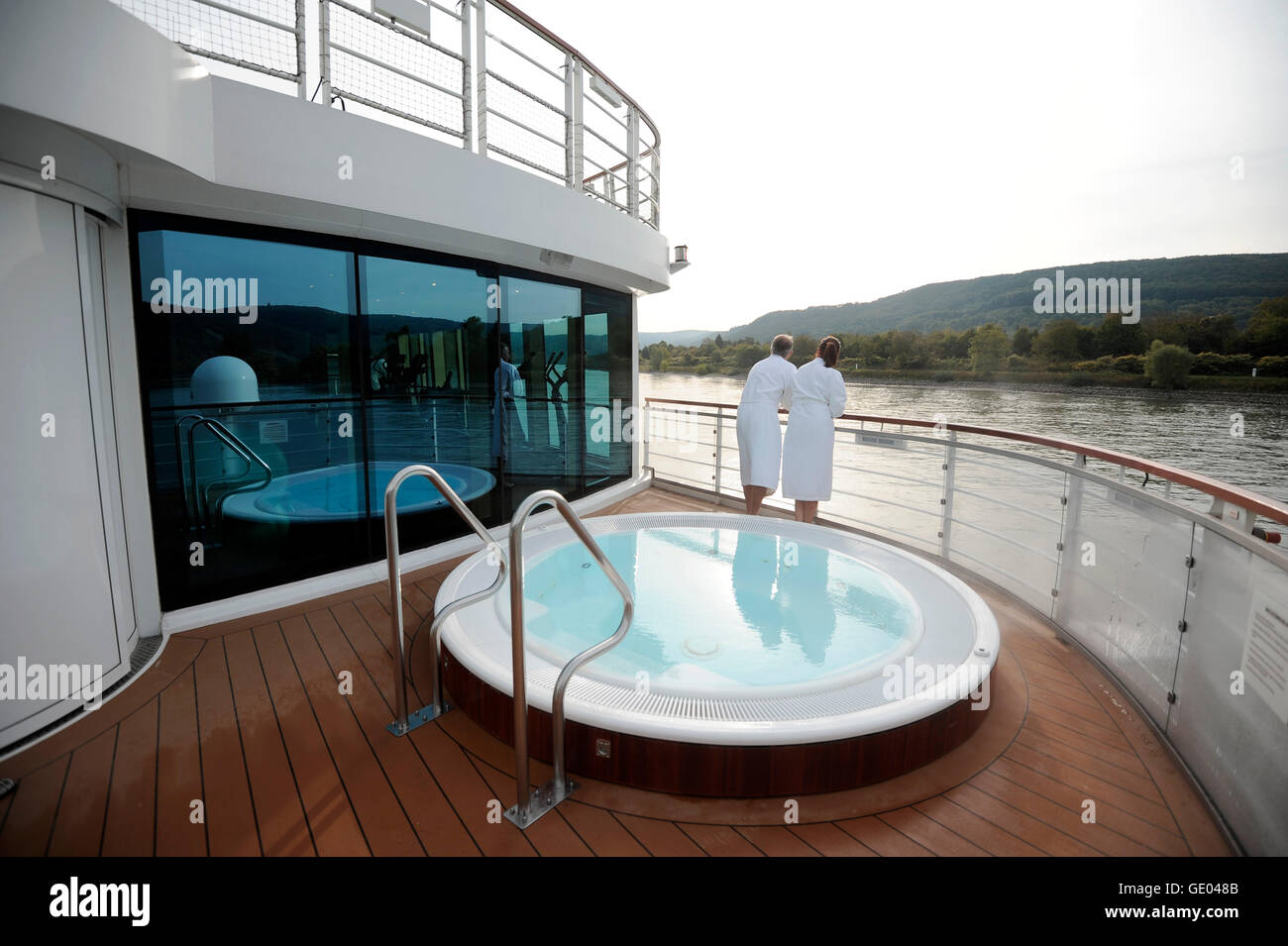 Two people in dressing gowns near a jacuzzi on the deck of a river ...
