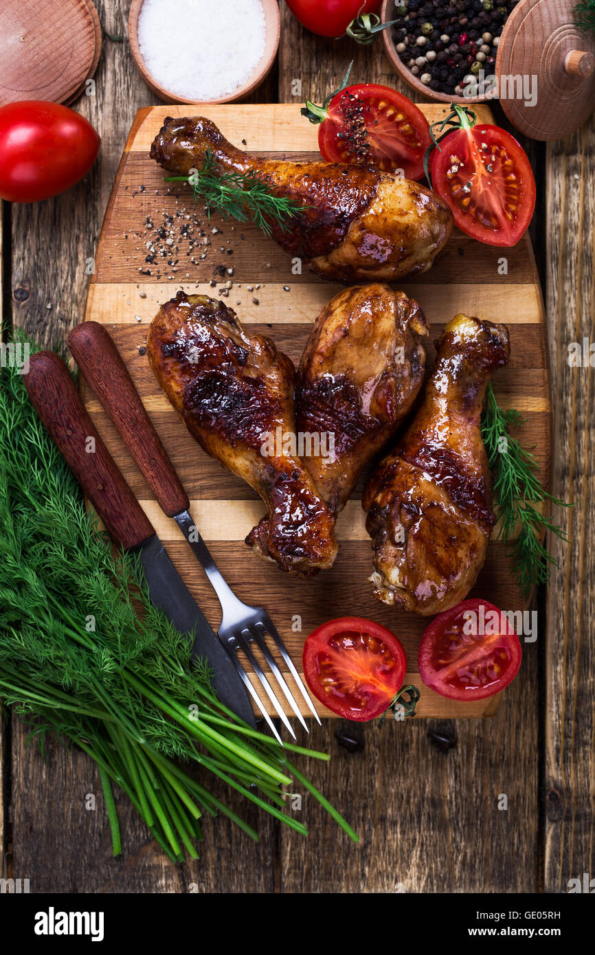 Homemade roasted chicken legs on rustic wooden board viewed from above ...