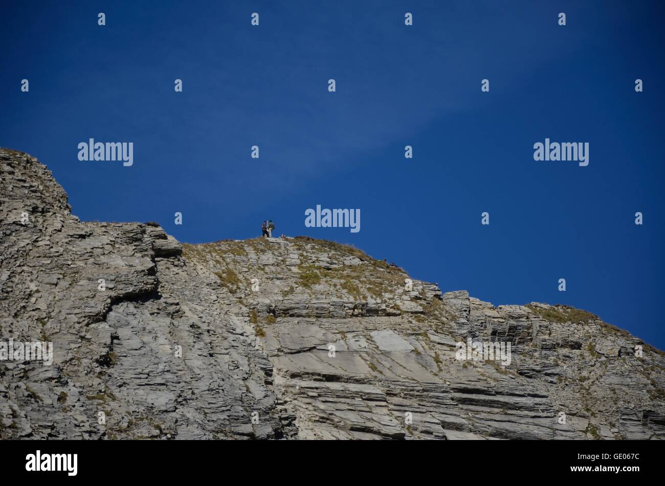 Two men, mountain top, rocky, rocks, blue sky, copy space, grass, cliff ...