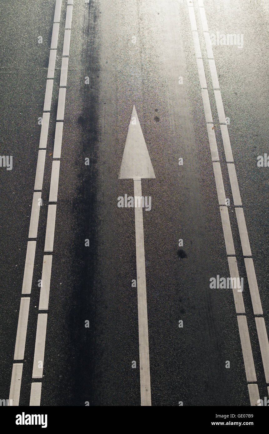 high point of view on a multi lane asphalt road with a white arrow for ...