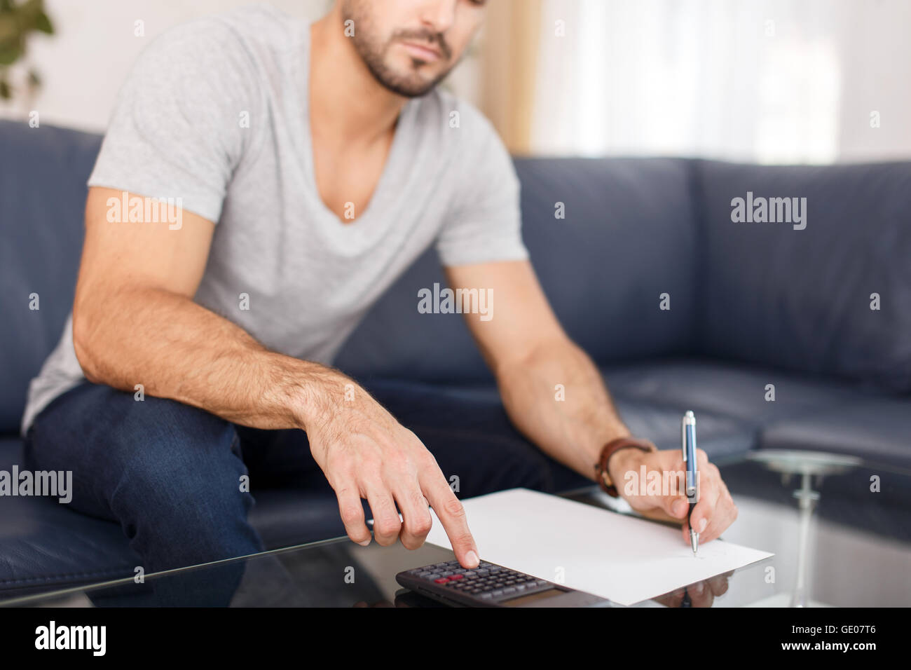Young casual man calculating on desk, black paper and calculator Stock ...