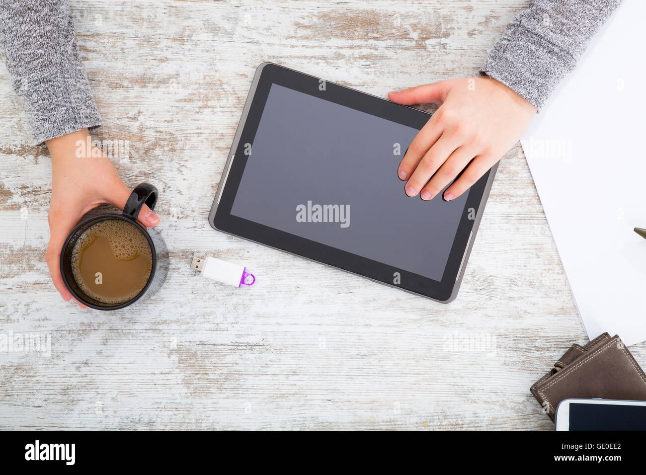 A woman’s hand at a table useing a tablet Stock Photo - Alamy