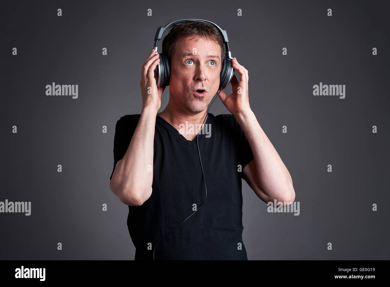 A middle age listening some music on the headphone and singing Stock ...