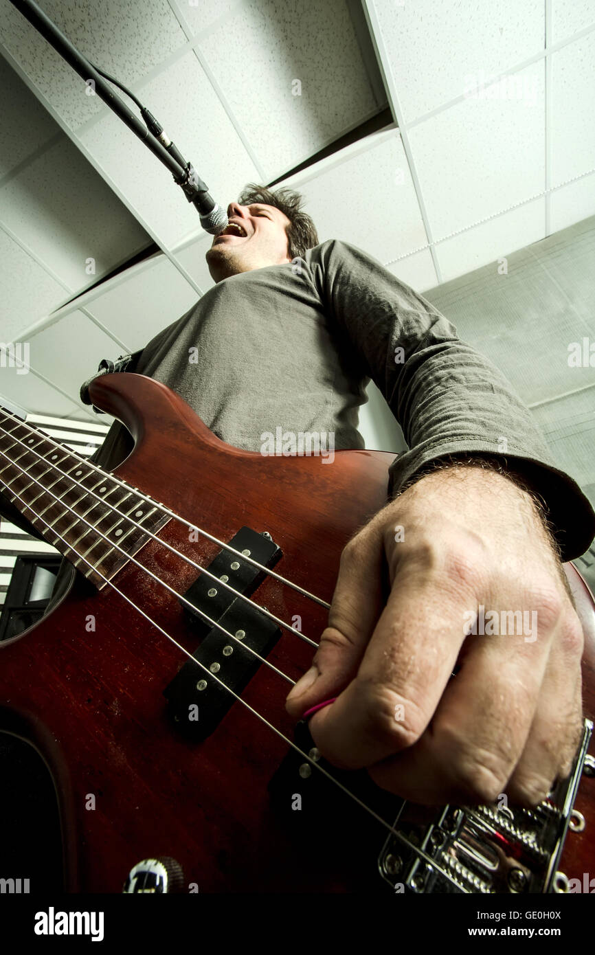 A Rock musician playing passionately bass in the rehearsal Studio Stock ...