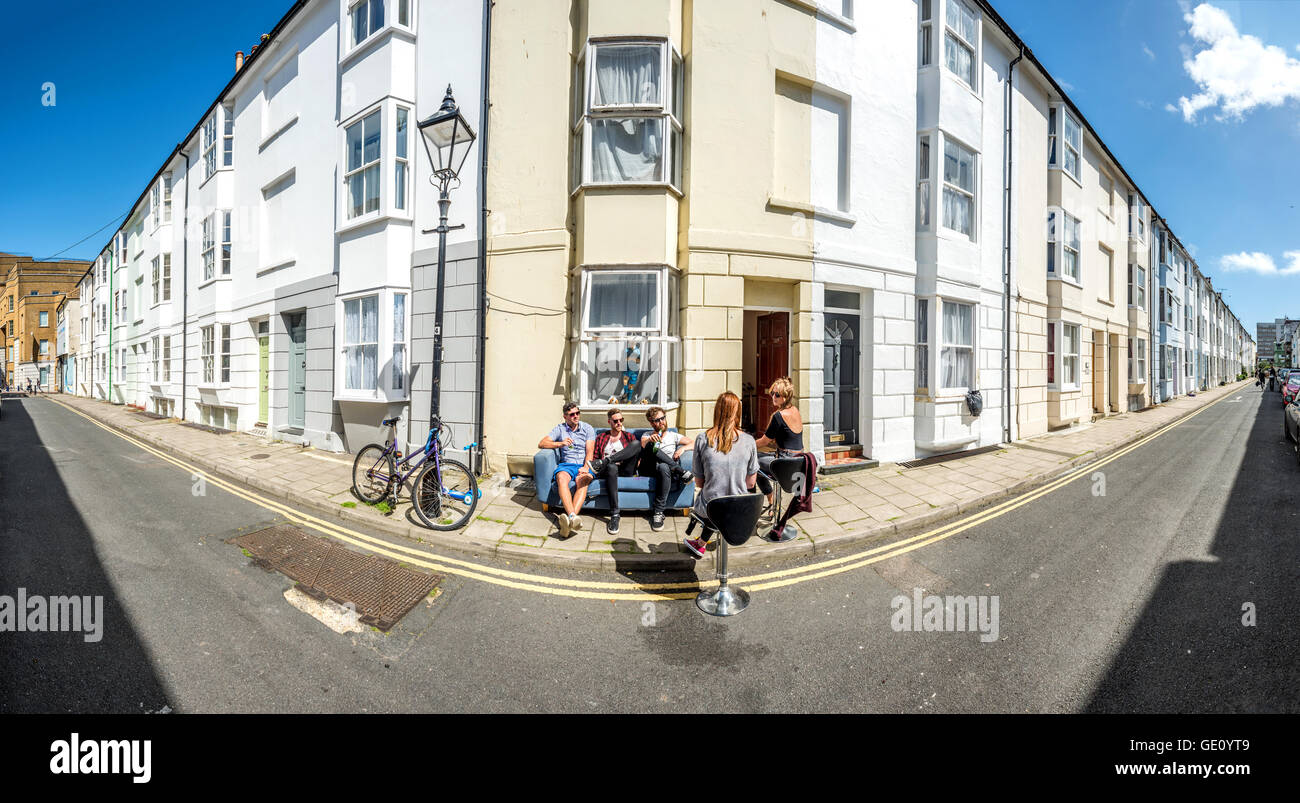 Young people sitting on the street outside their house on a summer's ...