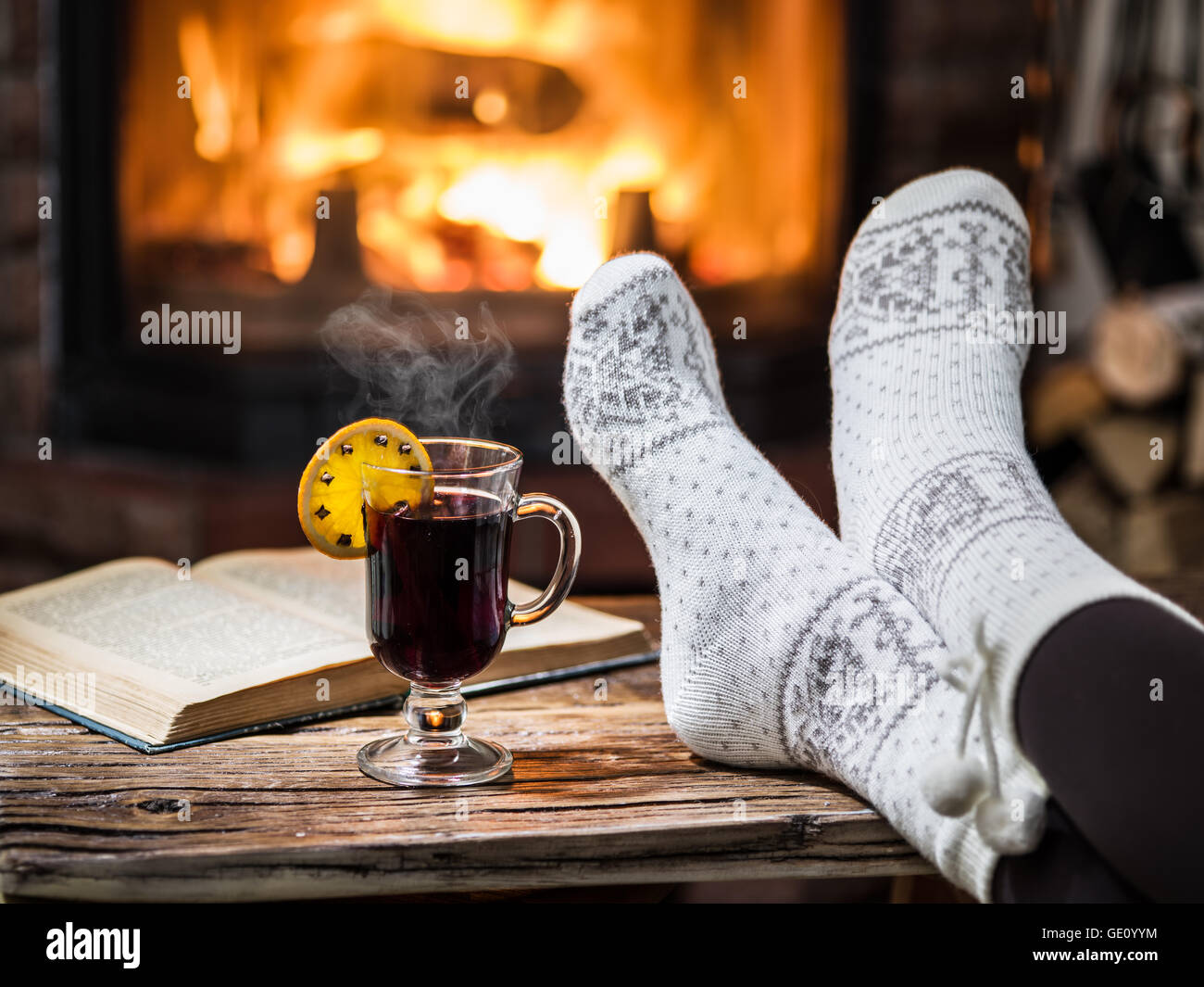 Warming and relaxing near fireplace. Woman feet near the cup of hot ...