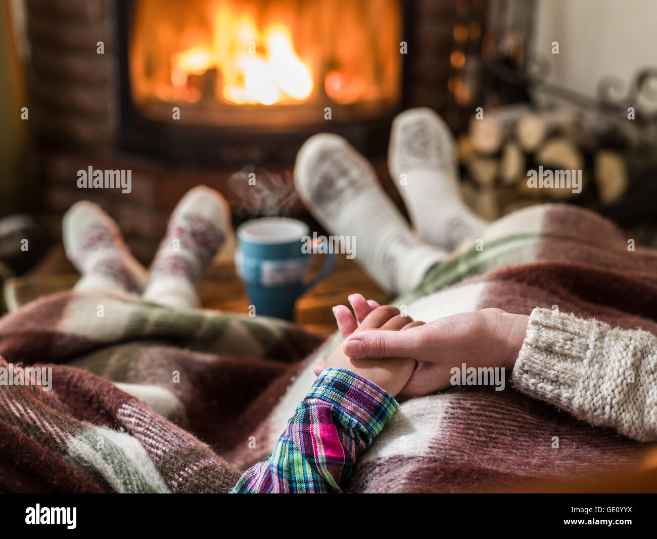 Warming and relaxing near fireplace. Mother and daughter holding hands ...