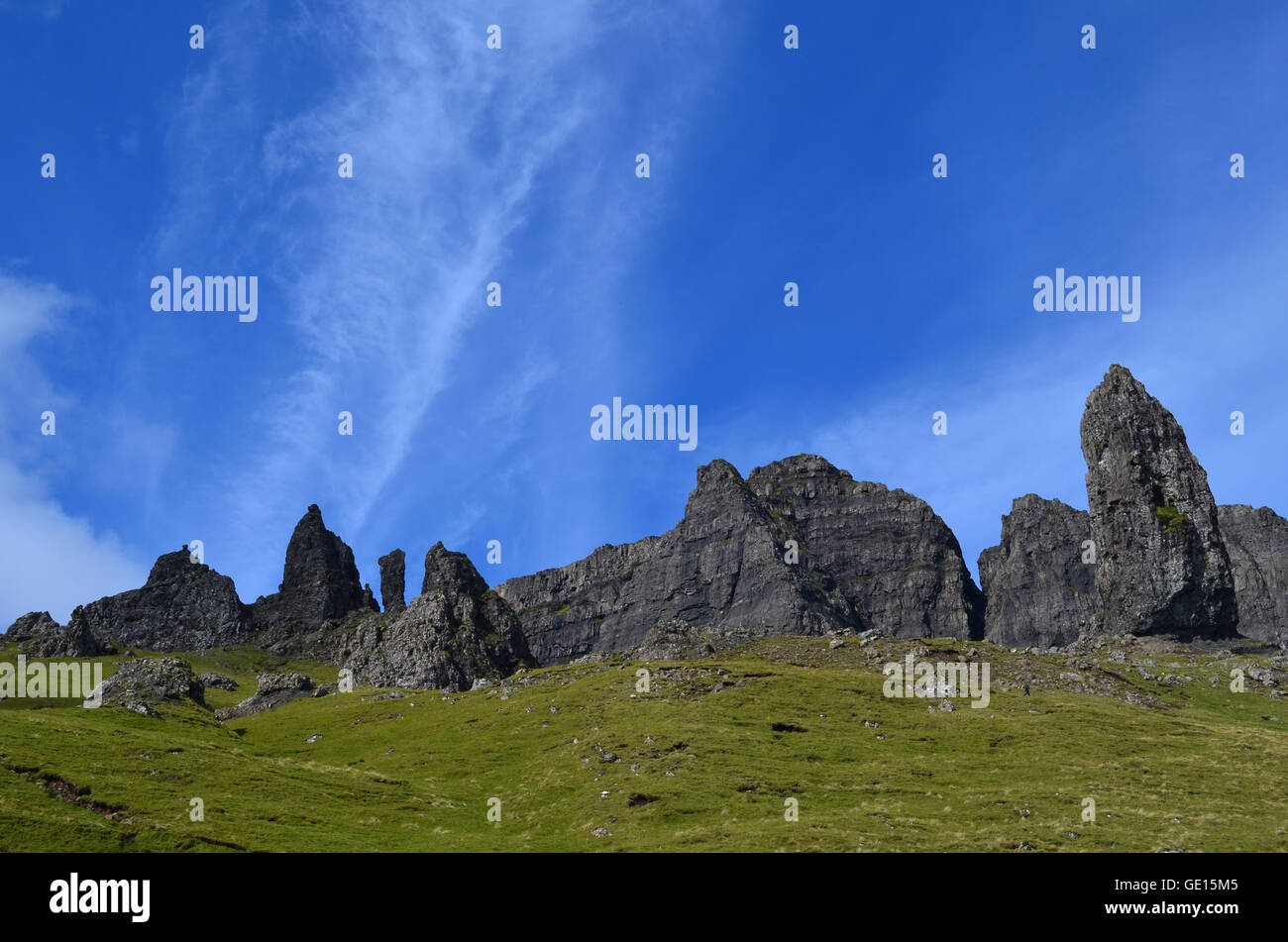 Rock formations on the Isle of Skye with green rolling hills and blue ...