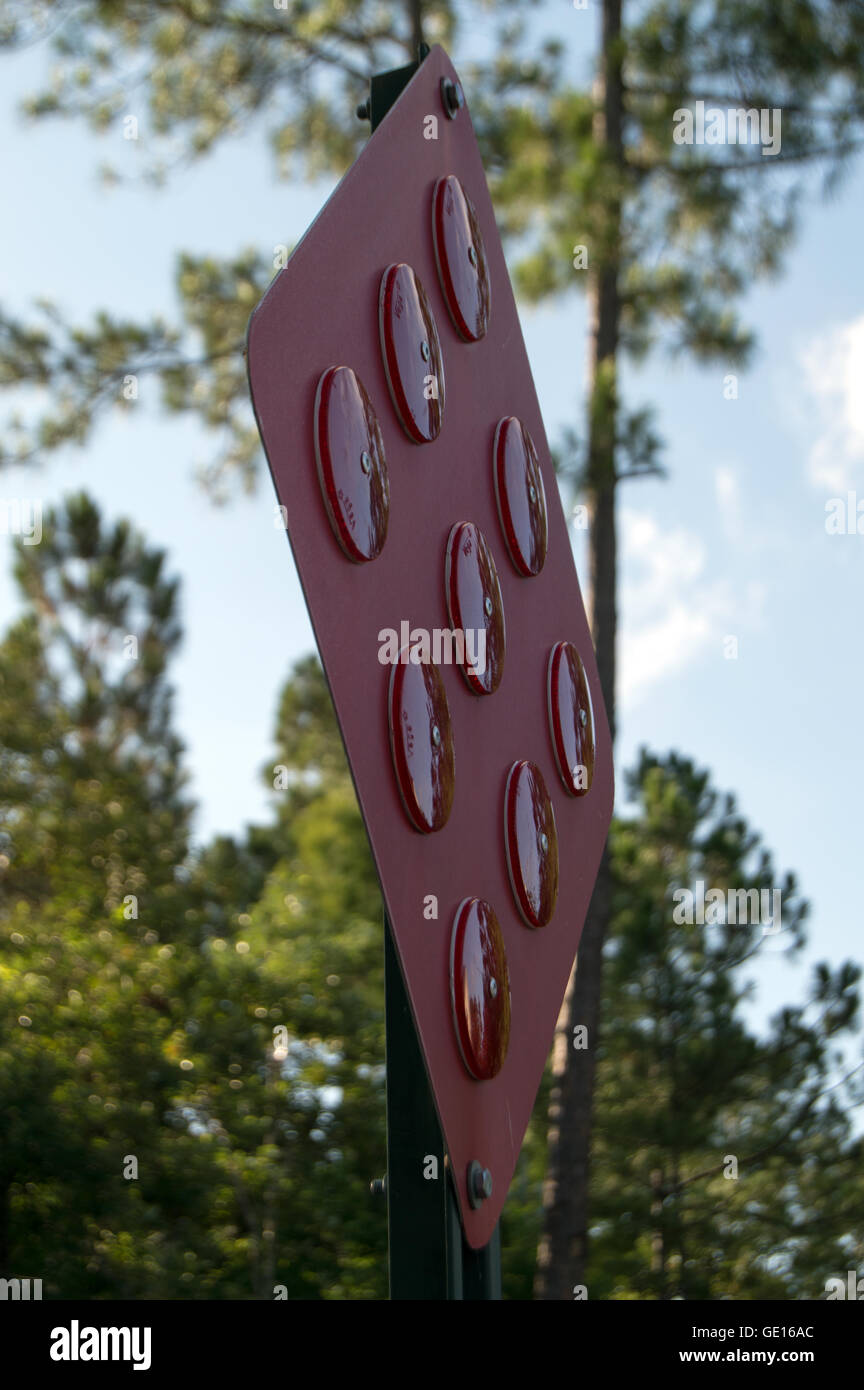 A red reflective sign with a bright blue sky and trees behind it Stock ...