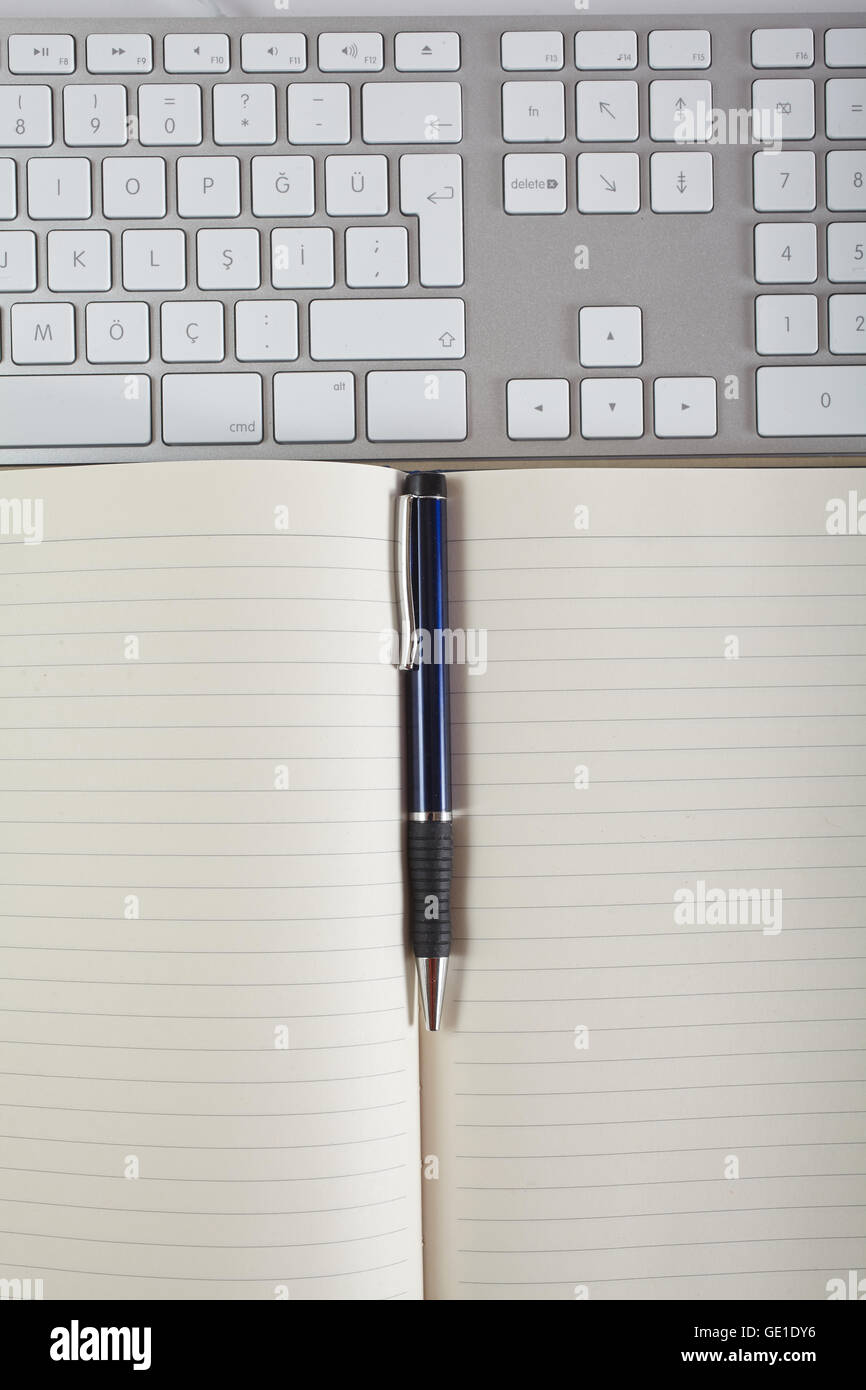 Top view office workplace - keyboard, pen and notebook on white table ...