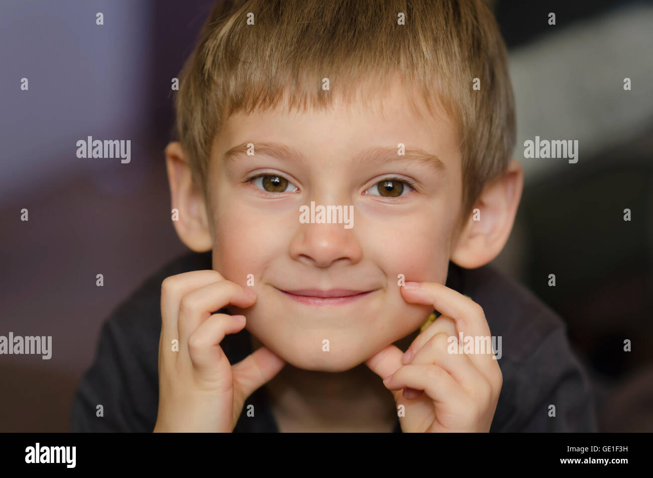 Portrait of a smiling boy with hands on his chin Stock Photo - Alamy