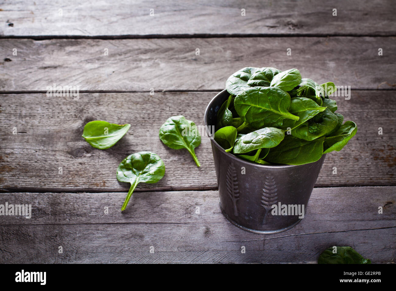 Baby spinach in metal bucket on old wooden surface. Spinach leaves ...