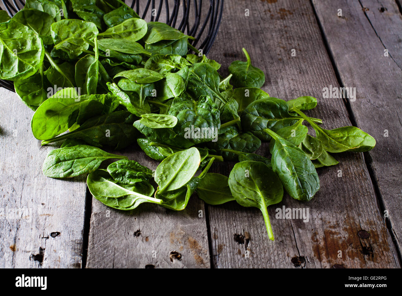 Baby spinach falling out of the metal basket on wooden background Stock ...