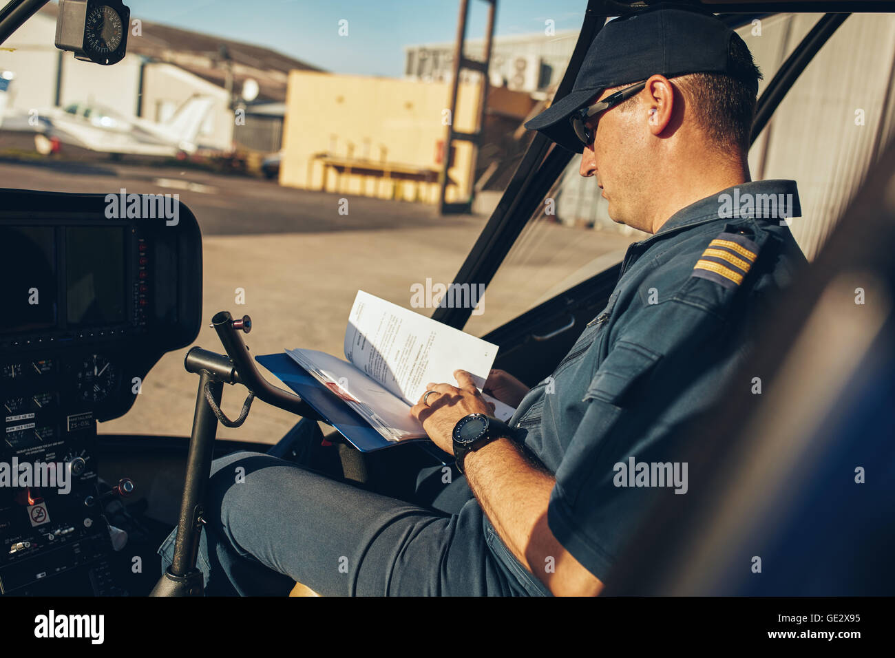 Helicopter pilot reading a manual book while sitting in the cockpit ...