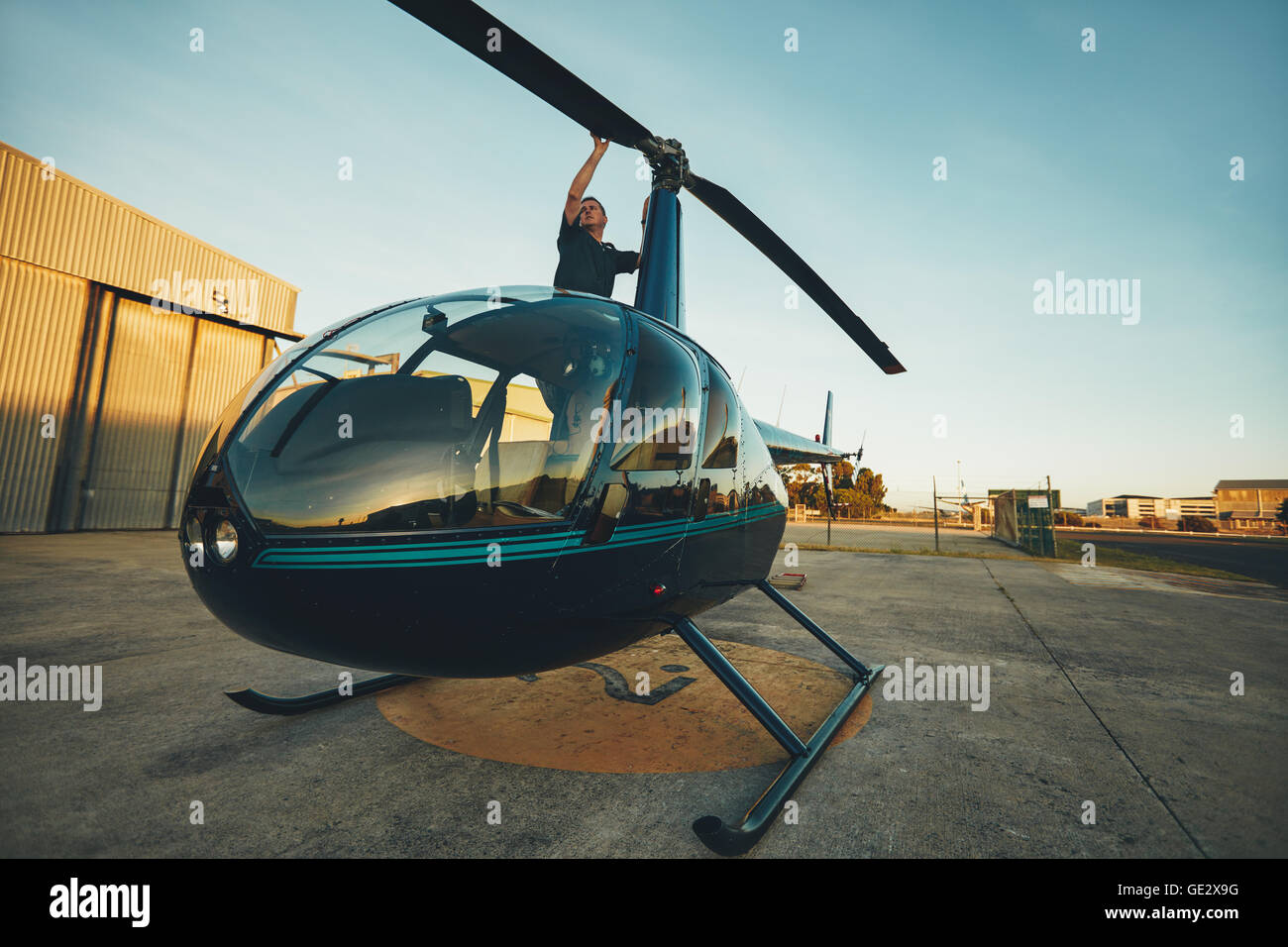 Image of pilot checking the helicopter rotor blades at the airfield ...