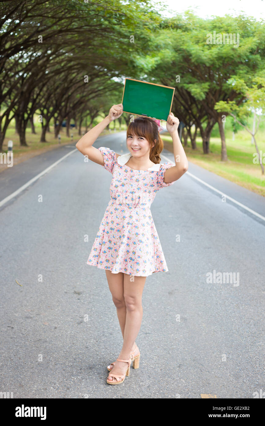 Cute woman hand holding green blank board sign on road with tree ...