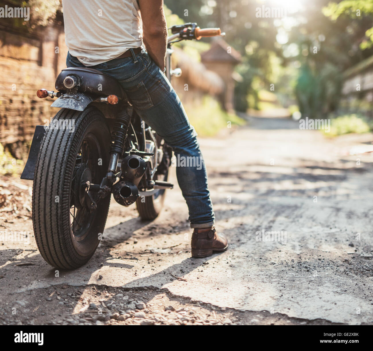Cropped shot of young man on his motorcycle on dirt road. Low section ...