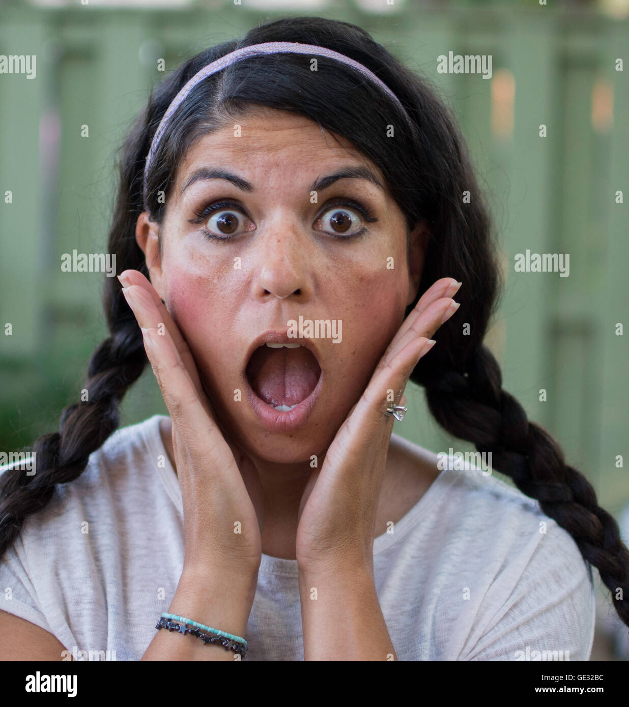 A surprised woman holds her face in alarm Stock Photo - Alamy