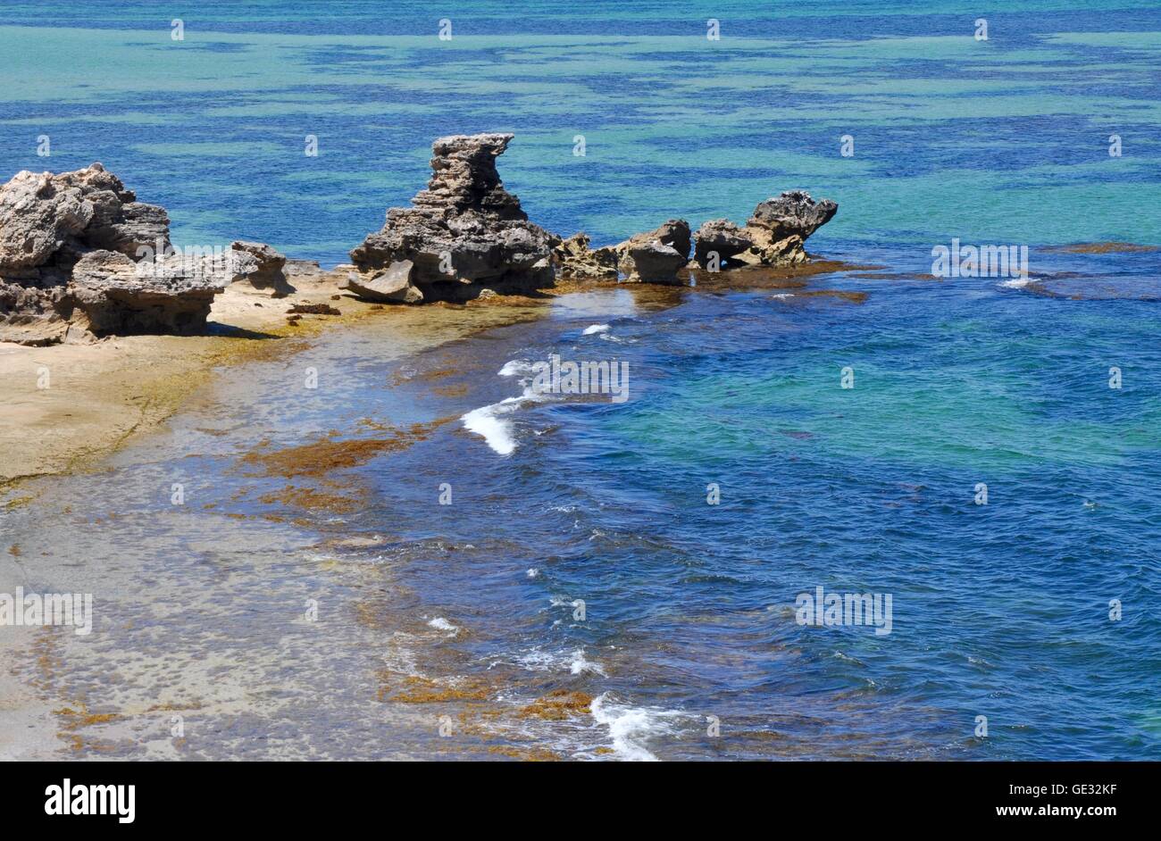 Turquoise-green Indian Ocean waters with rugged limestone rock outcrop ...