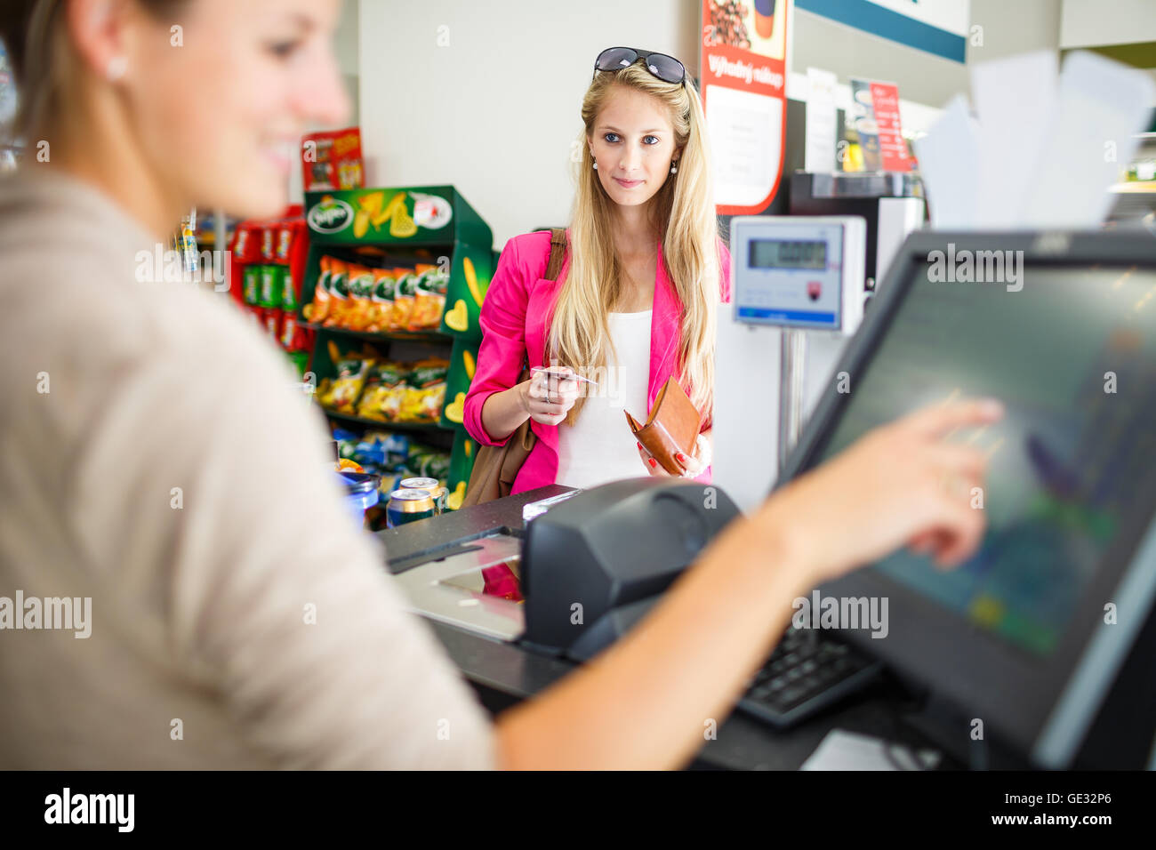 Beautiful young woman paying for her groceries at the counter of a ...