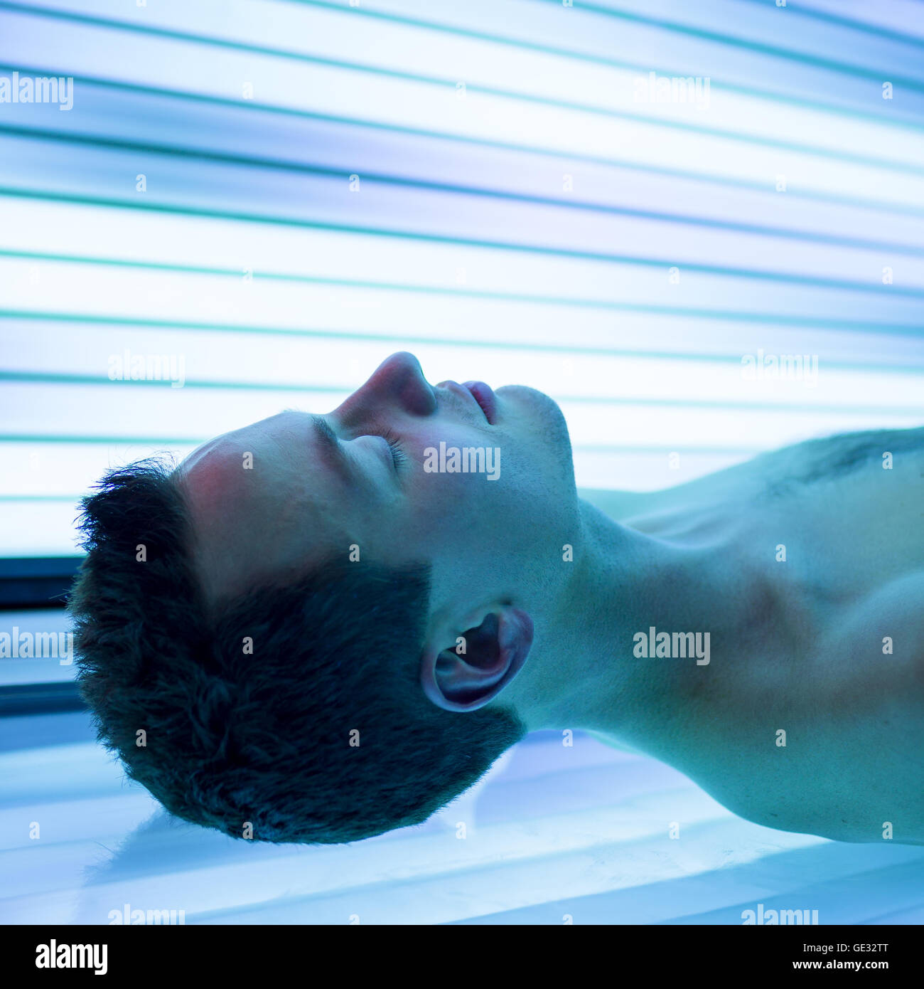 Handsome young man relaxing during a tanning session in a modern ...