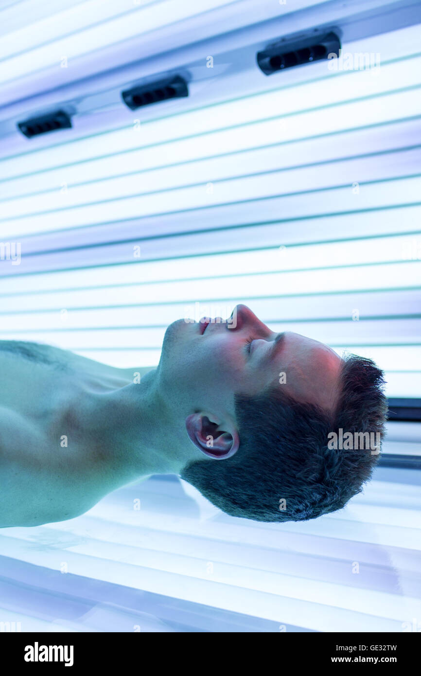 Handsome young man relaxing during a tanning session in a modern ...
