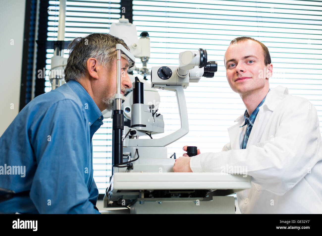 Optometry concept - senior man having his eyes examined by an eye ...