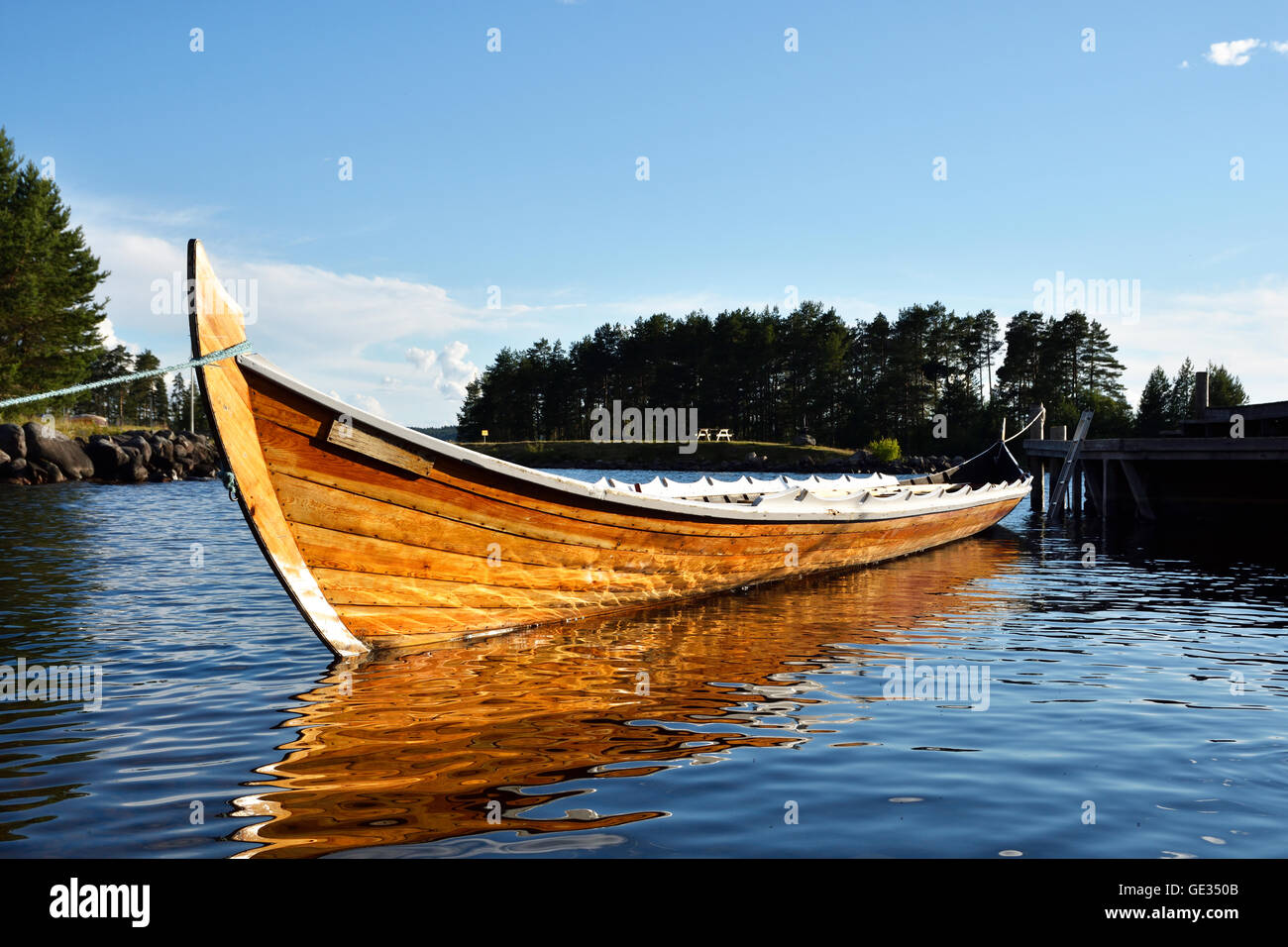 Long rowing boat laying in the water with blue sky in background ...