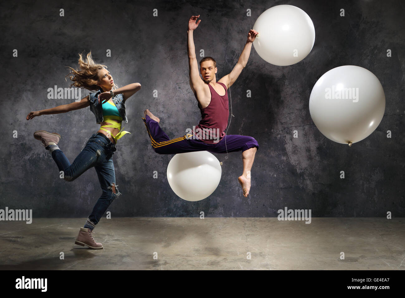 A pair of dancers in a jump in the arrangement with the big balloons ...